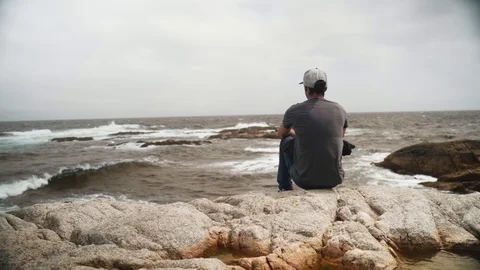 A man seen from behind sit down on some ... | Stock Video | Pond5