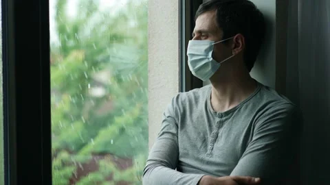 Man on self-isolation in a mask looks ou... | Stock Video | Pond5