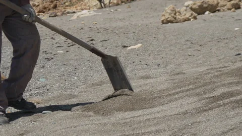 A man is shoveling sand on a beach near ... | Stock Video | Pond5