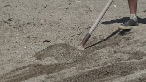 A man is shoveling sand on a beach near ... | Stock Video | Pond5