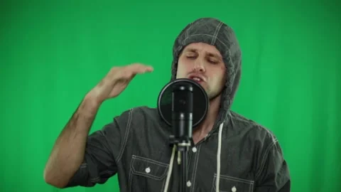 A man sings into a microphone on a green... | Stock Video | Pond5