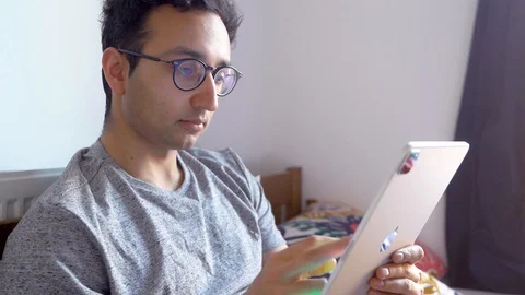 Man sitting in bed with silver iPad Pro,... | Stock Video | Pond5