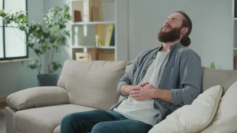 Man sitting on the couch suddenly felt p... | Stock Video | Pond5