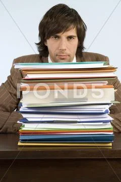 Man sitting on desk with stack of files, portrait ~ Hi Res #27083033