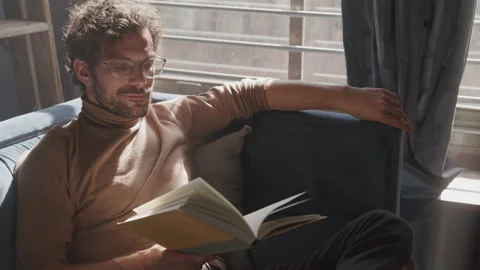 Man Sitting Down Reading a Book | Stock Video | Pond5