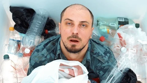 man sitting in a pile of plastic | Stock Video | Pond5