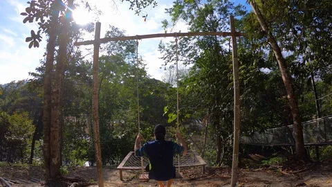 Man sitting on rope swing | Stock Video | Pond5