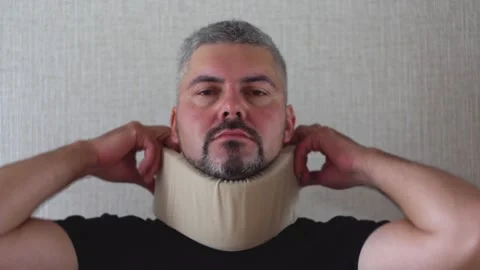 A man with a sore neck puts on a medical... | Stock Video | Pond5