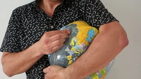 Man squeezing the air out of globe beach... | Stock Video | Pond5