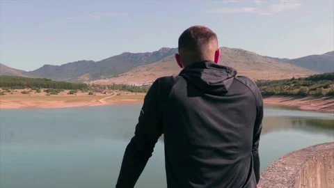 Man standing on a dam of a lake sightsee... | Stock Video | Pond5
