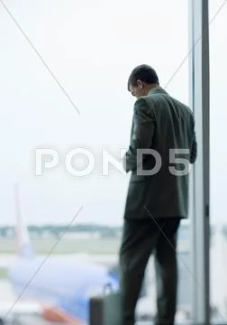 Man standing looking down, airplane in background Stock Photo #42165715