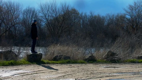 A man standing on a rock throwing a ston... | Stock Video | Pond5