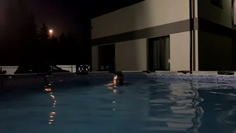 man swimming in night pool at moonlight | Stock Video | Pond5
