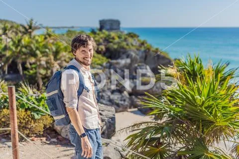 Man tourist enjoying the view Pre-Columbian Mayan walled city of Tulum ...