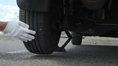 Man turns car wheel with puncture on jac... | Stock Video | Pond5