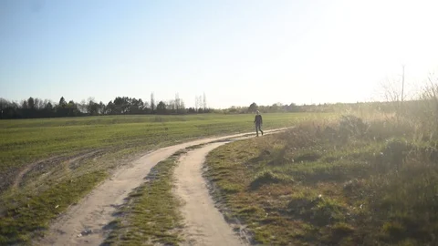 man walking along a path in a green fiel... | Stock Video | Pond5