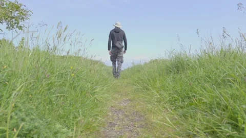 Man walking away from camera on grassy p... | Stock Video | Pond5