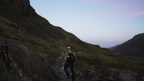 A man walking a dark wet mountain path | Stock Video | Pond5
