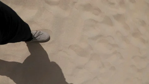 A man walking on footprints in the sands... | Stock Video | Pond5