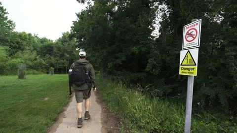 A man walking past a sign for danger dee... | Stock Video | Pond5