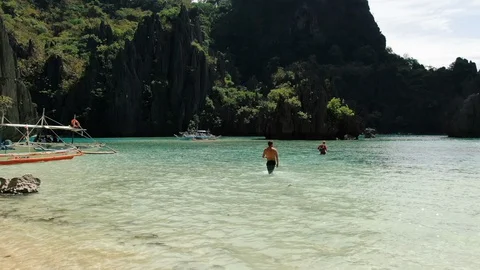 Man walking into a pristine blue lagoon ... | Stock Video | Pond5