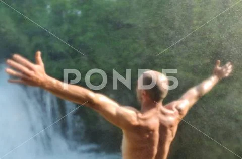 Photograph: Man waterfall standing man with wide opened arms with ...