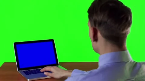 Man working at a laptop with blue screen... | Stock Video | Pond5
