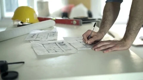 Man writing notes on blueprints by table... | Stock Video | Pond5