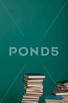 Many books stacked on a table on a green background in the science ...