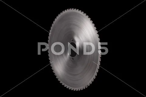 Photograph: Massive spinning circular saw blade isolated on black ...