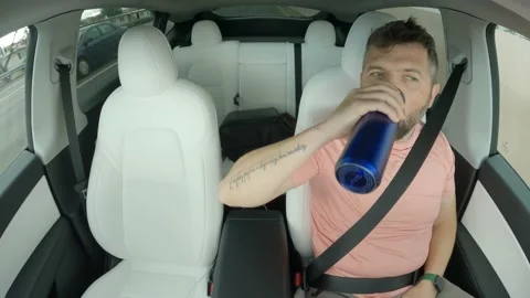 Mature driver drinking water in Tesla Mo... | Stock Video | Pond5
