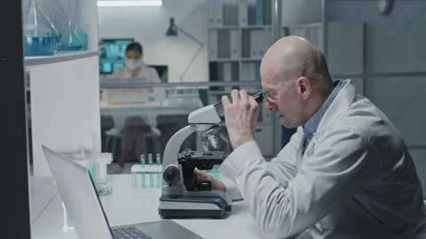 Mature Man Using Microscope | Stock Video | Pond5