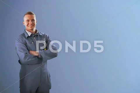 Mechanic standing in front of a blue background ~ Hi Res #21944273