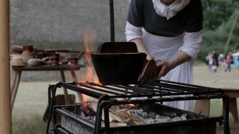 Medieval woman fanning fire under cookin... | Stock Video | Pond5