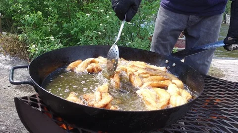 Men cooking fried fish by a lake | Stock Video | Pond5