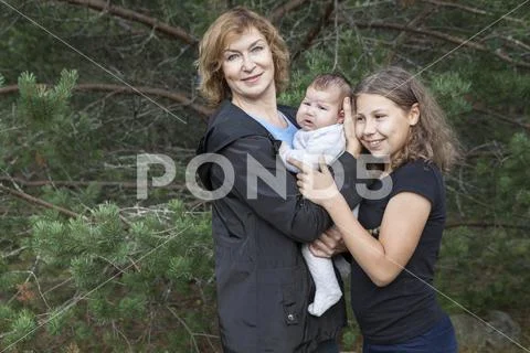 Middle age Caucasian woman with infant on arms and preteen girl ...