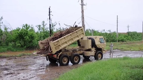 Military dump truck moving tree debris | Stock Video | Pond5