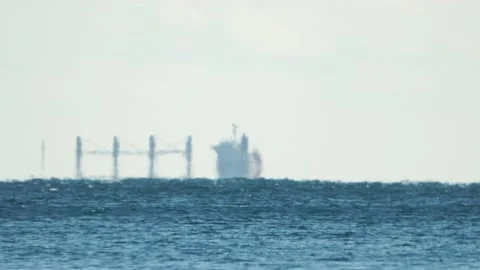 Mirage of cargo ship in the sea beyond t... | Stock Video | Pond5