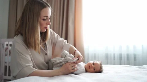 mom changing dress baby on bed in bedroo... | Stock Video | Pond5