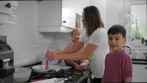 Mom multitasking in the kitchen with two... | Stock Video | Pond5