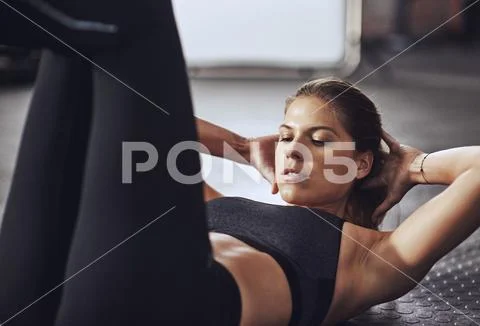 More sweat now, less jiggle later. a young woman working out at the gym ...