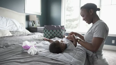 Mother changing baby son's diaper on bed | Stock Video | Pond5