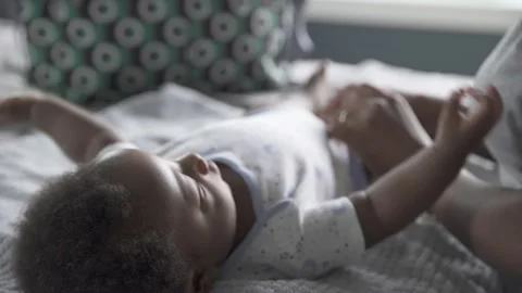 Mother changing baby son's diaper on bed | Stock Video | Pond5