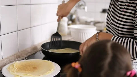 Mother is cooking pancakes on the kitche... | Stock Video | Pond5