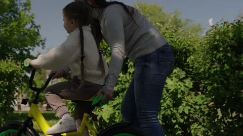 mother daughter, little girl rides bike,... | Stock Video | Pond5