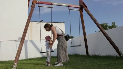 Mother helps cute girl sitting and pushi... | Stock Video | Pond5