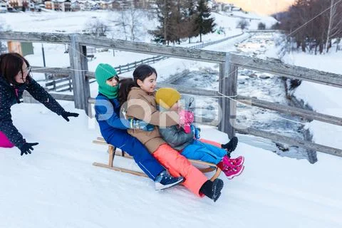 Mother pushing wooden sled with her three daughters on snow slope ~ Hi ...