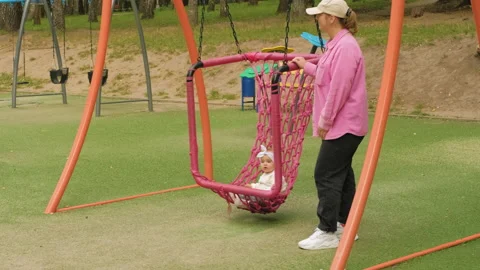 Mother rocking her child on a playground... | Stock Video | Pond5
