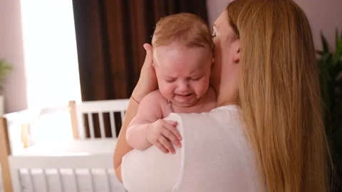 A mother soothes a crying baby in her ar... | Stock Video | Pond5