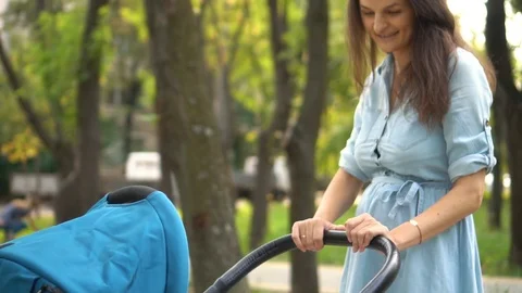 Mother walking with a pram in the park. ... | Stock Video | Pond5